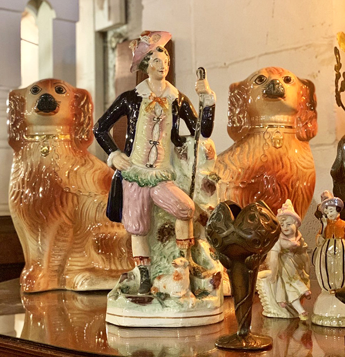 These Staffordshire dogs stand guard beside a colorful figurine, showcasing the kind of conversation pieces that make dinner guests do double-takes.
