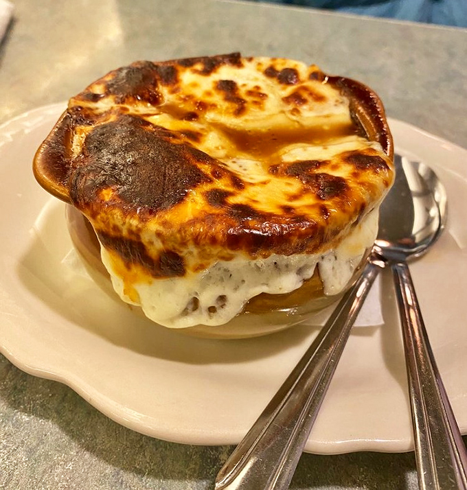 French onion soup with a cheese pull that would make Instagram weep. Beneath that golden canopy lies savory, soul-warming perfection.