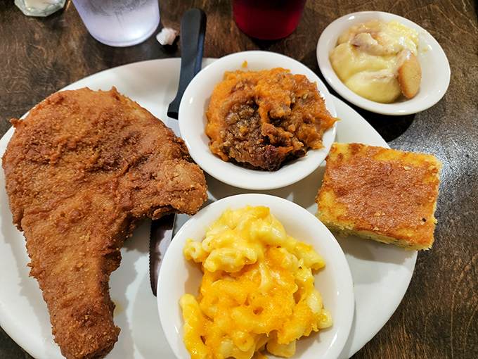 Southern comfort on a plate: golden fried pork chop, mac and cheese that's unapologetically orange, and sides that make vegetables actually worth eating.