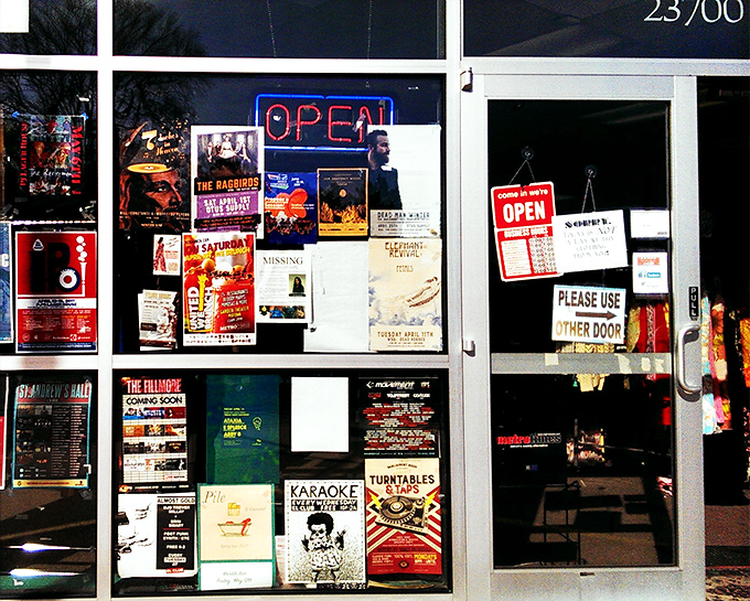 The storefront's collage of concert posters and event flyers serves as a cultural bulletin board for the community.