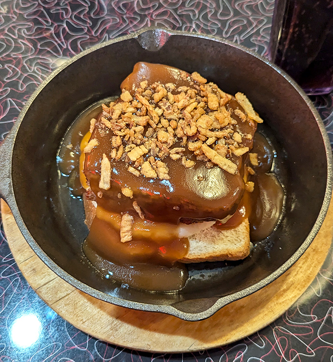 This isn't just meatloaf; it's a gravity-defying tower of comfort food engineering, swimming in gravy that could make a vegetarian question their life choices.