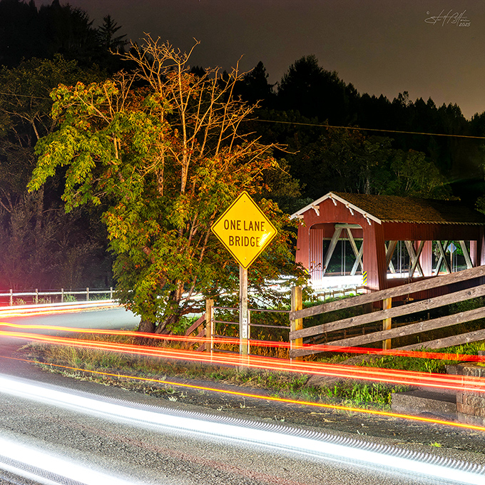 As darkness falls, the bridge transforms into a glowing lantern of history, its warm light cutting through the night like a beacon from the past.