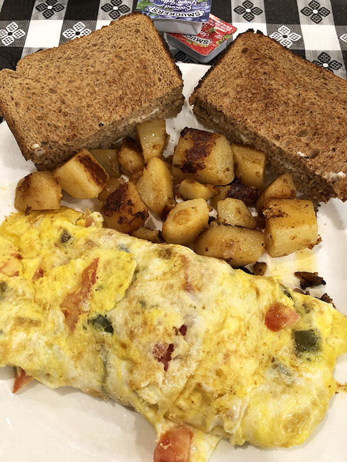Breakfast of champions: an omelet stuffed with veggies and cheese, home fries with perfect crispy edges, and hearty wheat toast.