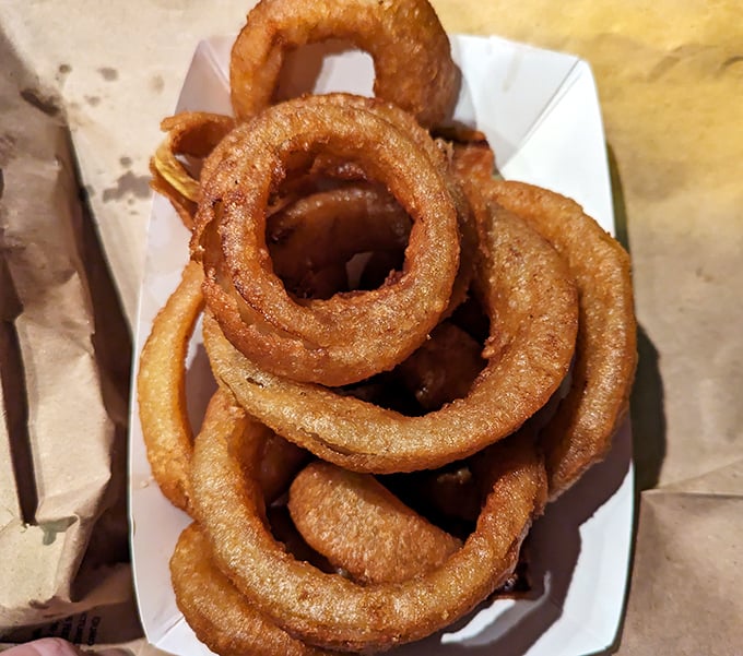 Onion rings stacked with the architectural precision of ancient monuments, except these were built to disappear in minutes.