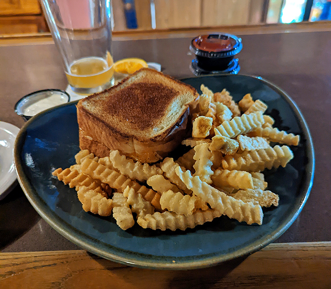 Comfort food architecture at its finest – golden crinkle fries surrounding a sandwich that's been kissed by the griddle gods.