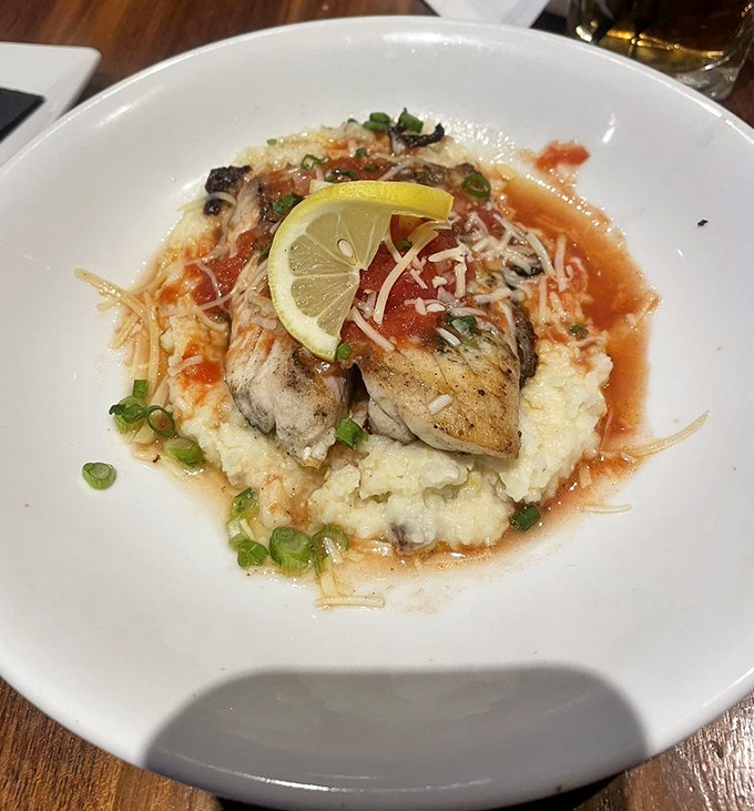 This red snapper perched atop creamy grits isn't just a meal; it's Southern hospitality with coastal flair, brightened by a squeeze of lemon.