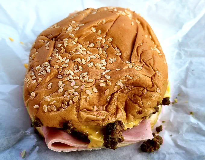 Layers of loose meat, ham, and cheese create a sandwich architecture that somehow defies gravity and good manners simultaneously.