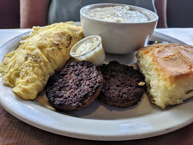 The classic Southern breakfast trinity: fluffy omelet, savory sausage patties, and a biscuit that would make your grandmother simultaneously proud and jealous.