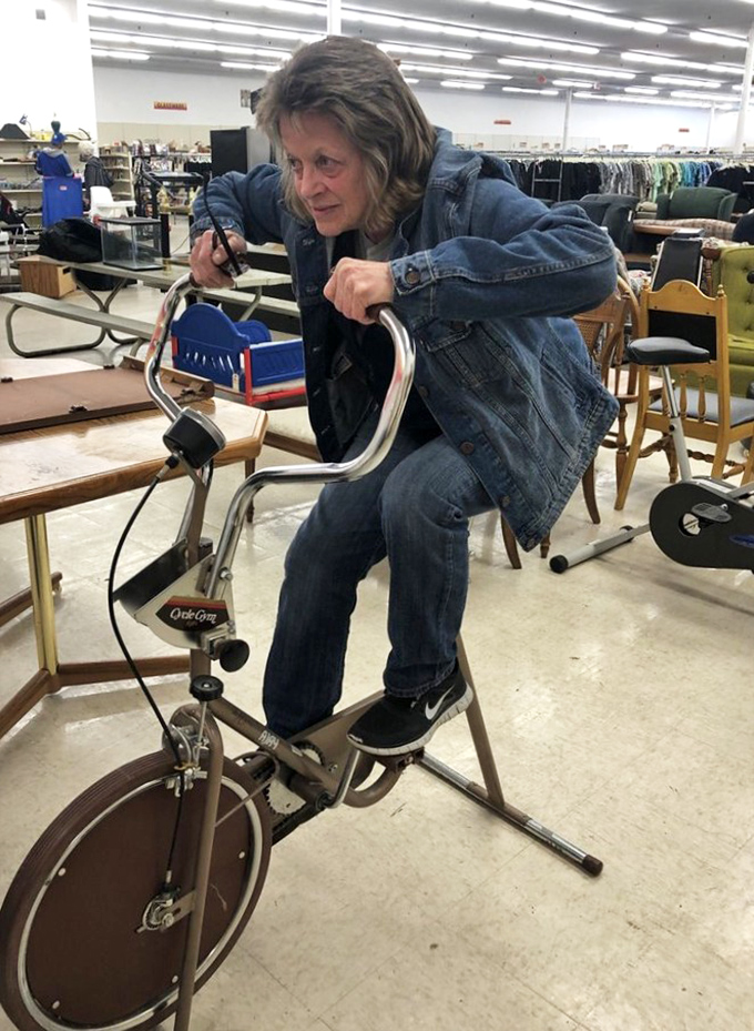"Does it still work?" A shopper test-drives a vintage exercise bike, proving thrift stores are interactive adventures.