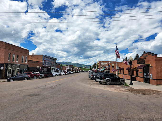 Main Street unfurls beneath dramatic Montana skies, where American flags flutter in the mountain breeze and every building tells a story of resilience.