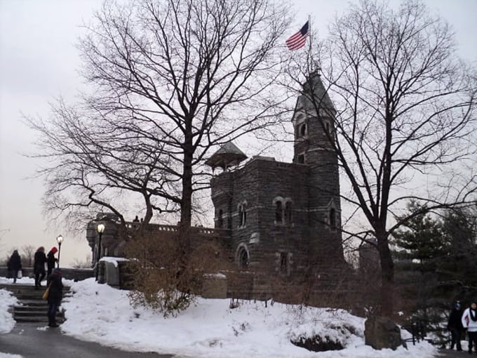 Winter's embrace turns Belvedere Castle into a snow-dusted wonderland. The American flag stands proud against bare trees and gray skies.