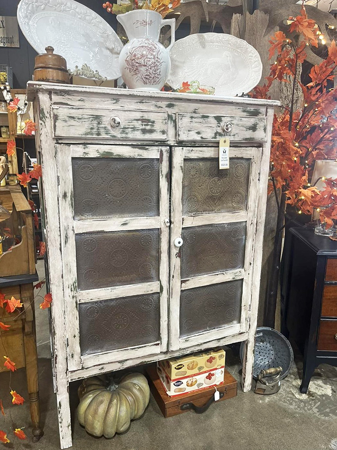 This distressed white pie safe with punched tin panels whispers stories of grandma's kitchen while offering stylish storage for modern homes.