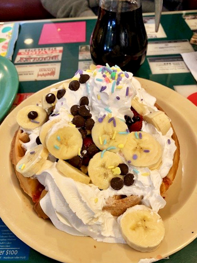 Not just a waffle &ndash; a masterpiece! Whipped cream mountains, fresh bananas, chocolate chips, and colorful sprinkles create breakfast's answer to modern art.