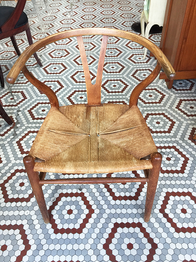 The iconic wishbone chair with its woven seat sits atop a geometric tile floor&mdash;a masterclass in timeless design that still feels fresh today.