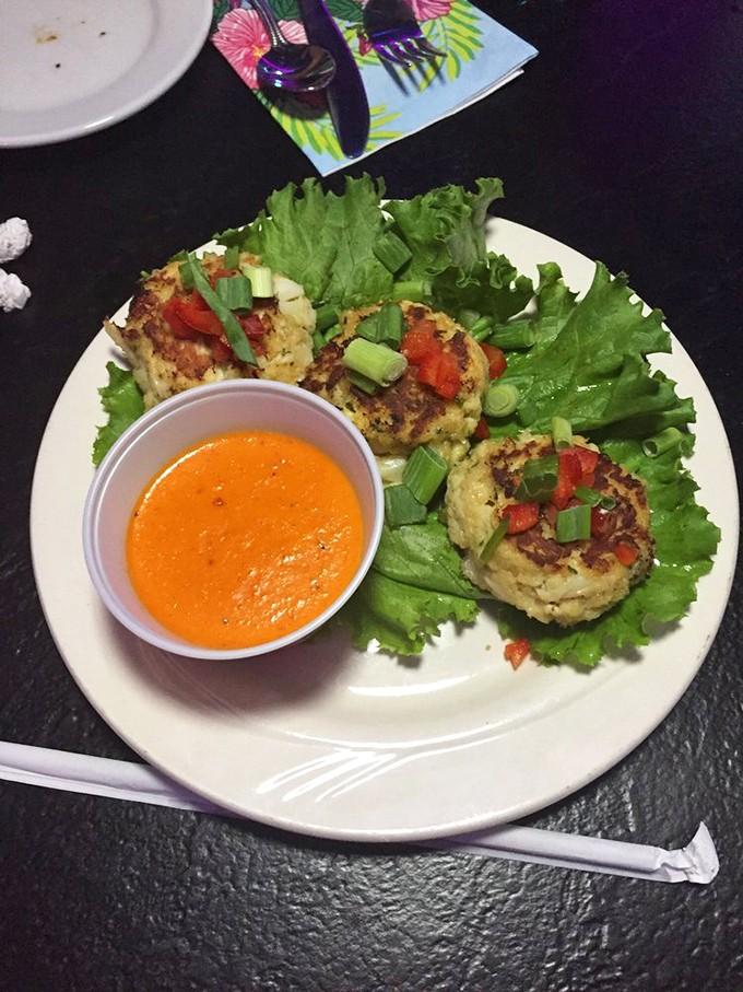 These crab cakes arrive like little golden treasures, paired with vibrant sauce that promises oceanic flavors in every bite.