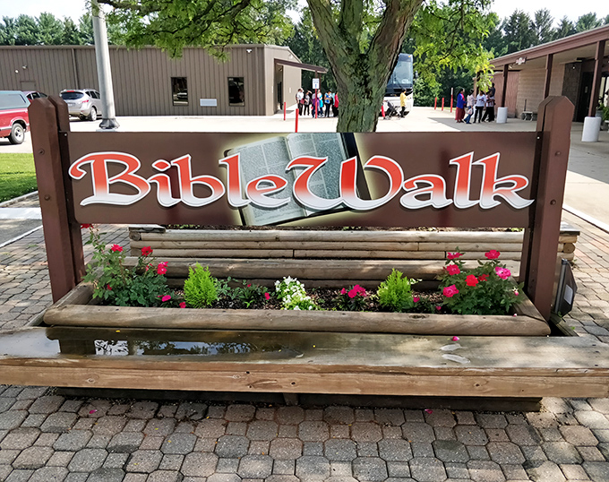 The unassuming sign for BibleWalk sits amid colorful flowers, inviting visitors to step into Biblical history through wax art.