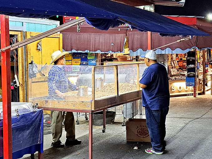 That glass display case holds mysteries while shoppers gather around like kids at a candy store window.