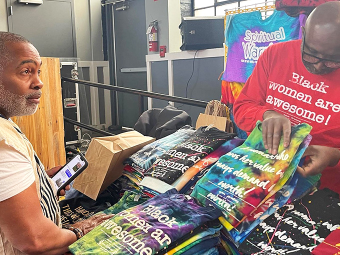 Tables display colorful t-shirts with empowering messages, celebrating community and culture through wearable art and expression.