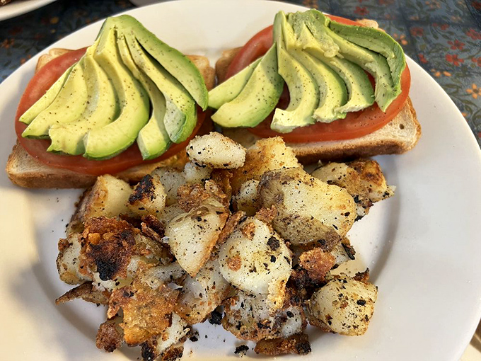 Avocado toast that doesn't require a second mortgage—vibrant, fresh, and paired with home fries that look like they've been individually introduced to seasoning.
