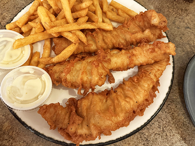 Batter-dipped fish with a golden crunch that echoes through the room, paired with fries so perfect they make ketchup seem like an unnecessary distraction.