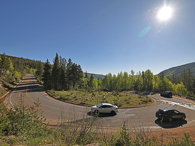 Hairpin turns reveal hidden valleys where cars look like colorful beetles navigating nature's magnificent playground.