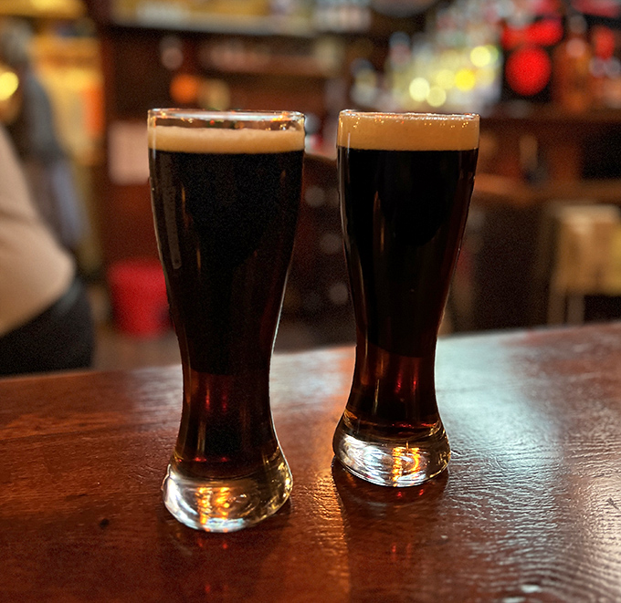 Two dark German beers stand tall and proud, their perfect foam caps like halos announcing their arrival from beer heaven.