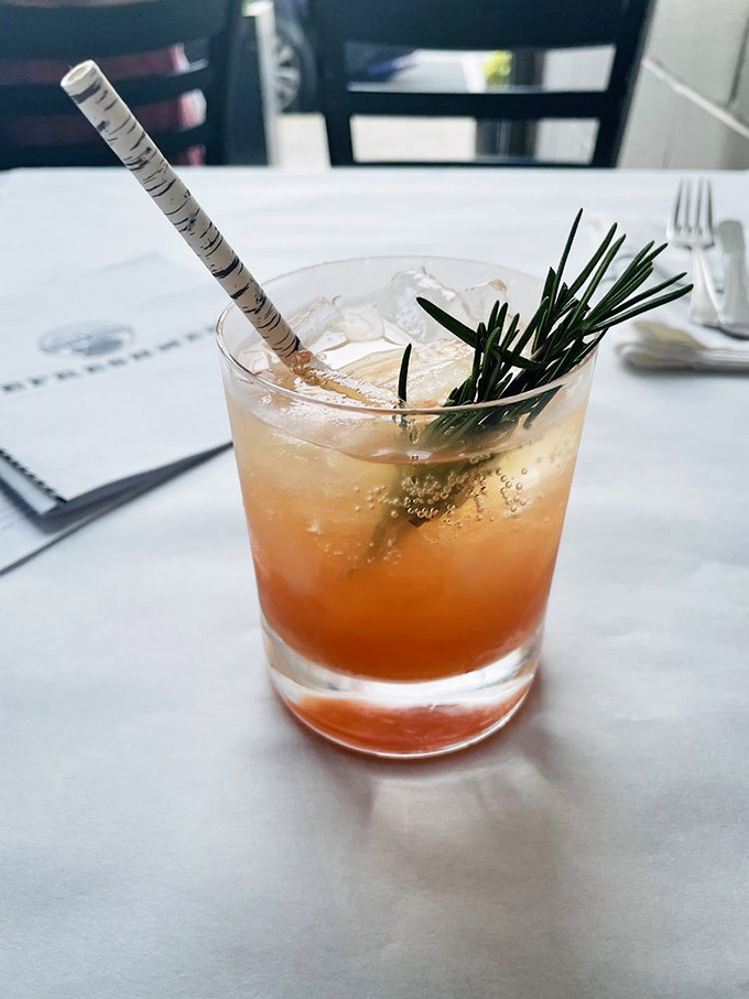 A cocktail garnished with rosemary that looks like it should be sipped slowly while contemplating life's greatest mysteries&mdash;or at least tonight's dessert options.