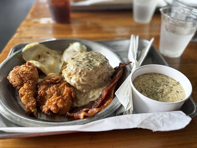Southern breakfast perfection on a metal tray&mdash;crispy fried chicken, bacon, and biscuits smothered in gravy that would make any grandma nod in approval.