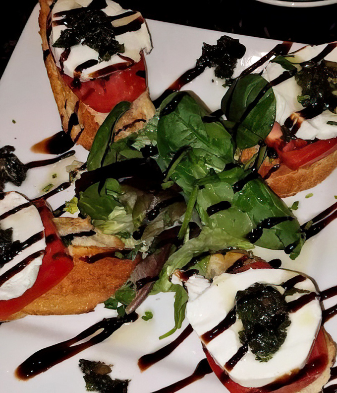Caprese bruschetta with a dramatic balsamic drizzle&mdash;proof that sometimes the simplest combinations create the most memorable flavors.