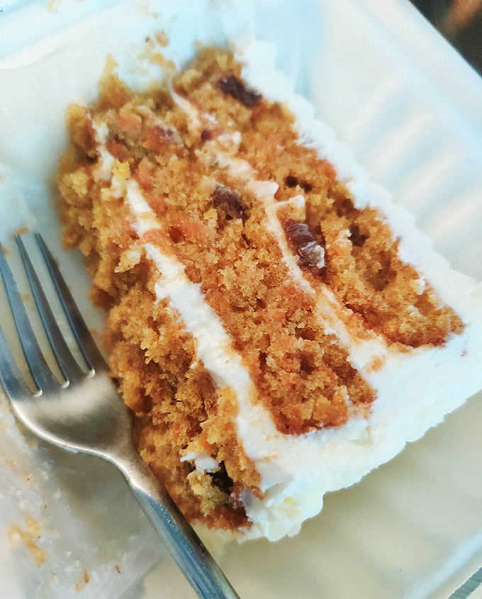A slice of carrot cake that doesn't pretend to be health food, with cream cheese frosting thick enough to leave evidence on your nose.