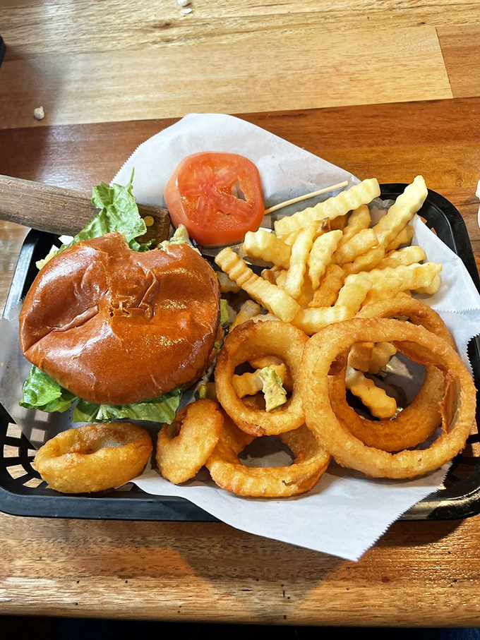 A burger that demands two hands and several napkins, flanked by golden fries and onion rings that make you forget you came for seafood.