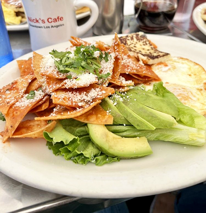 Nick's chilaquiles: where crispy tortilla chips swim in sauce, topped with cheese and avocado—Mexico's gift to morning hunger.