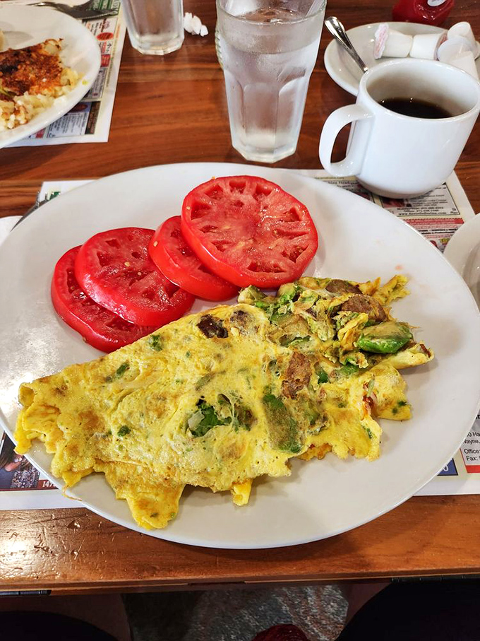 Breakfast artistry at work&mdash;a perfectly executed omelet with vibrant tomato slices that could make a summer garden jealous. Morning fuel that respects your taste buds.