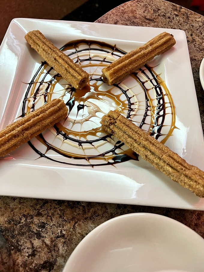 Churros arranged like the spokes of a delicious wheel, with chocolate and caramel creating a masterpiece that belongs in the Dessert Hall of Fame.