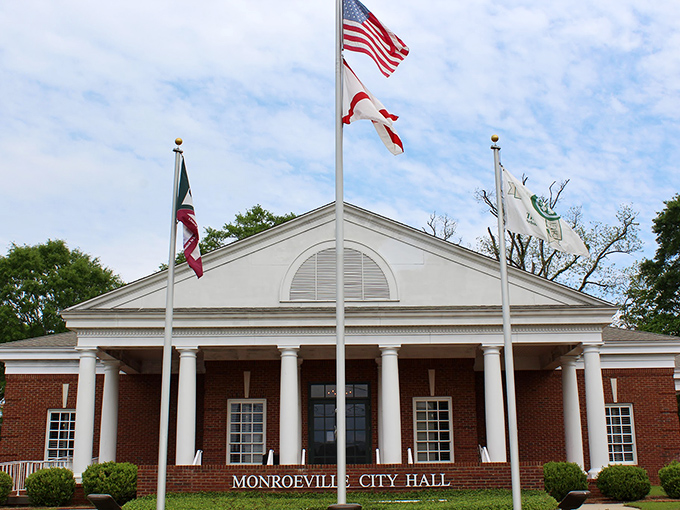 Monroeville City Hall stands as a testament to small-town civic pride, its columned entrance and flags creating an instantly recognizable landmark. 
