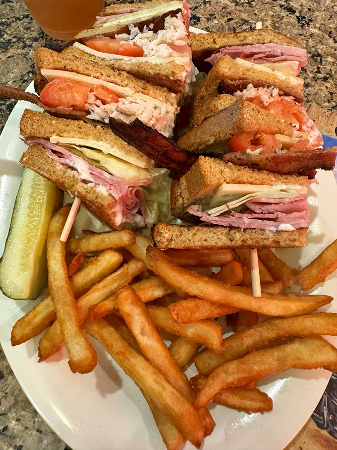 The club sandwich: architectural marvel of toast, meat, and veggies, served with a mountain of golden fries. Lunch doesn't get more classic than this.