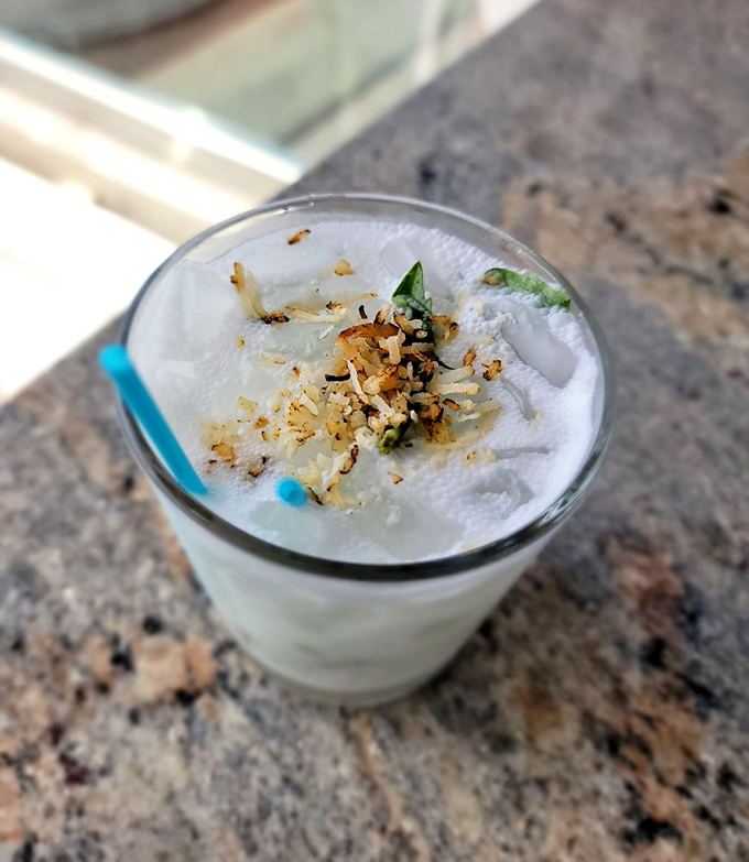 A cocktail that looks like a cloud and tastes like vacation. Topped with toasted coconut because someone in the kitchen really cares.