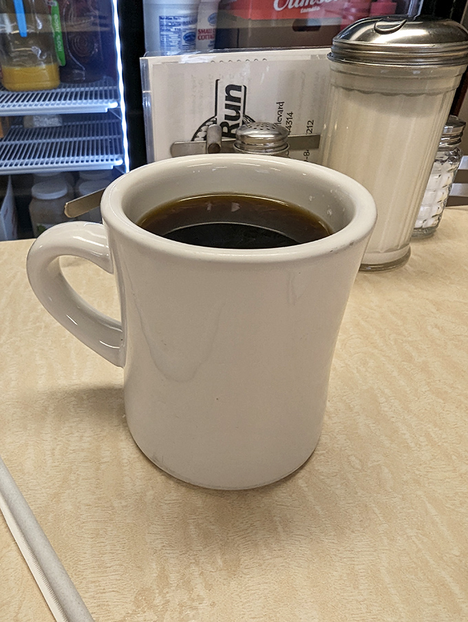 The coffee comes in sturdy mugs that mean business – no fancy latte art needed when the brew itself delivers such honest comfort.