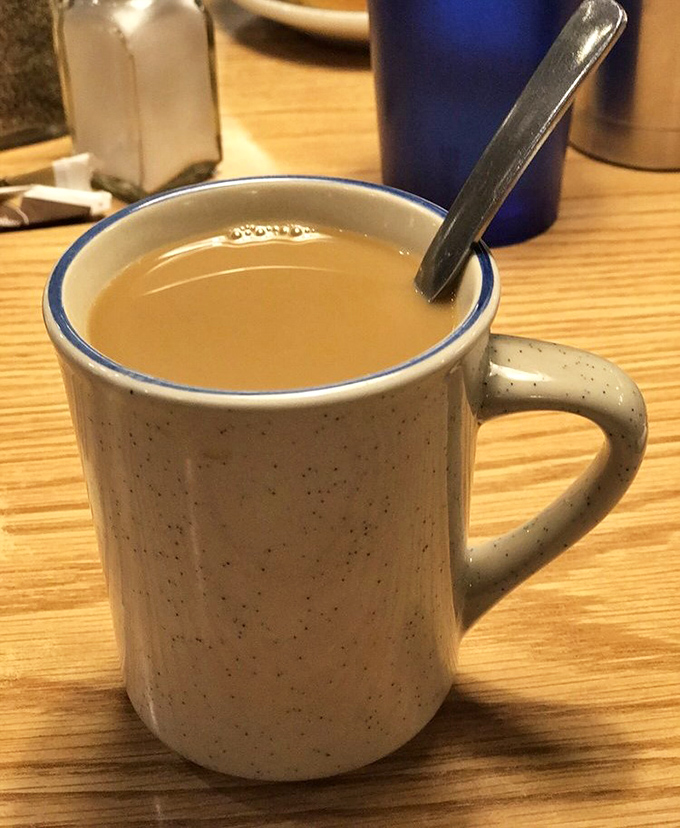 The coffee arrives in a speckled mug – not fancy, not pretentious, just honest diner brew that keeps your cup at the perfect level of full.