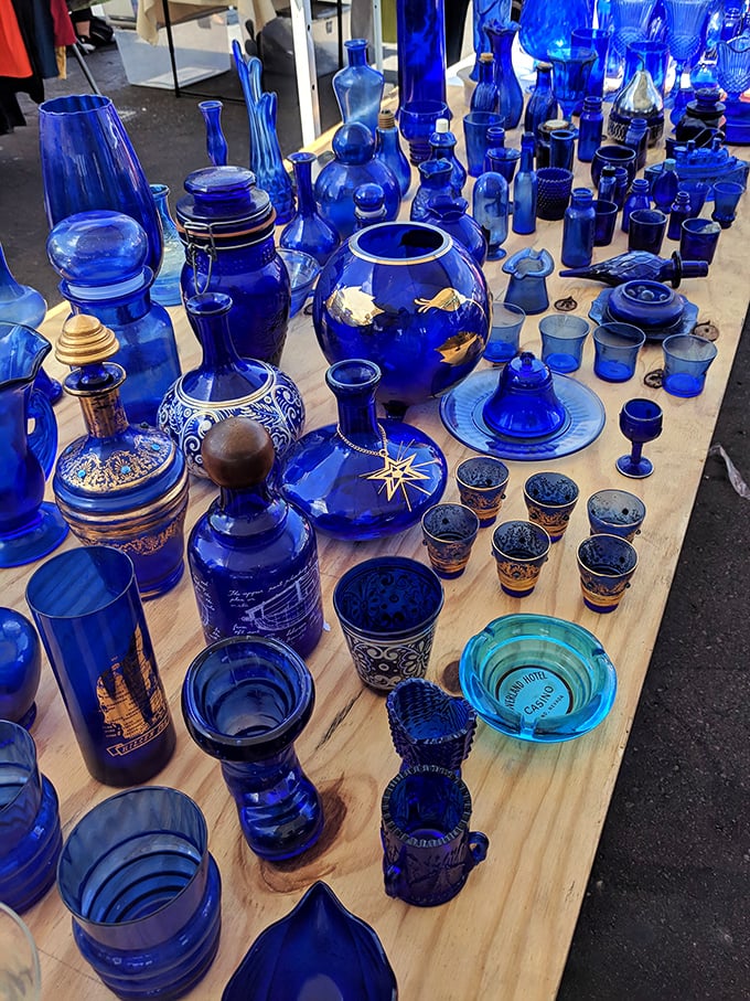 A sea of cobalt blue glassware catches the sunlight like Mediterranean waters, each vessel telling stories of elegant dinner parties from decades past.