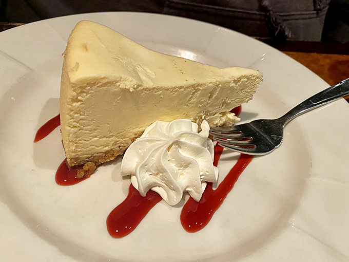 Cheesecake so creamy it should require a swimming certificate. That ribbon of raspberry sauce is the culinary equivalent of a perfect sunset.