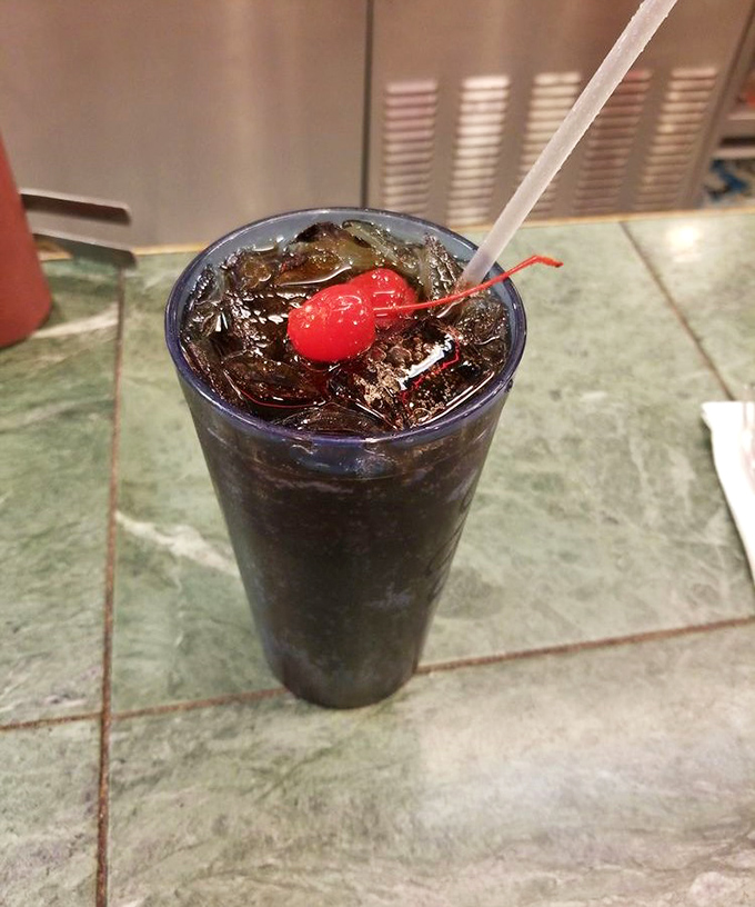 That cherry-topped soda isn't just a drink &ndash; it's liquid nostalgia served in a glass tall enough to hold childhood memories and adult-sized thirst.