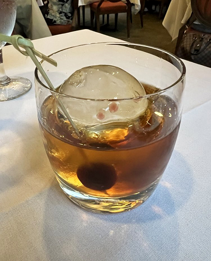 An Old Fashioned with a sphere of ice so perfect, it makes you wonder if there's a dedicated ice sculptor hiding behind the bar.