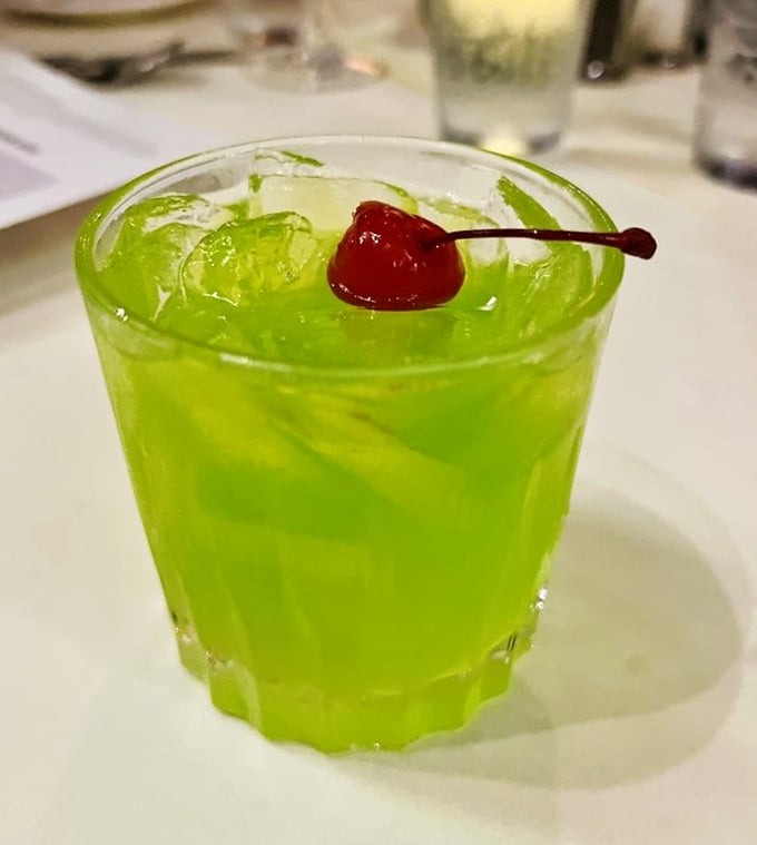 That bright green cocktail looks like liquid sunshine in a glass, complete with a cherry on top for extra festive vibes.