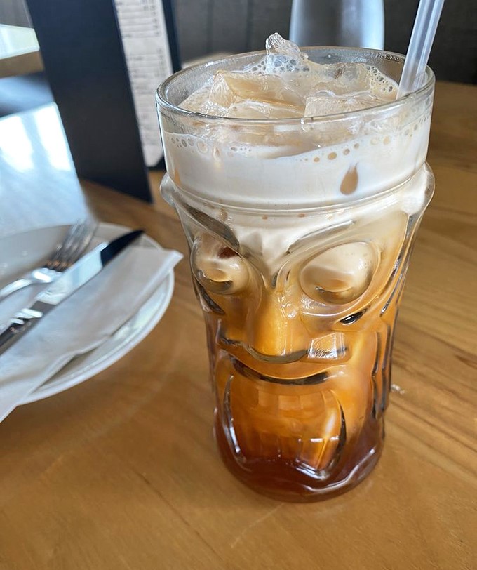 Thai iced tea served in a tiki glass &ndash; because sometimes your beverage deserves to wear a fun outfit while cooling down your spice-tingled taste buds.