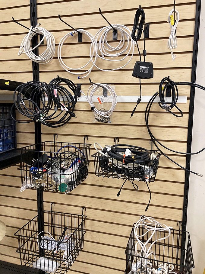 The technological graveyard where cables and cords of mysterious origin hang like electronic spaghetti, daring you to find their matching devices.
