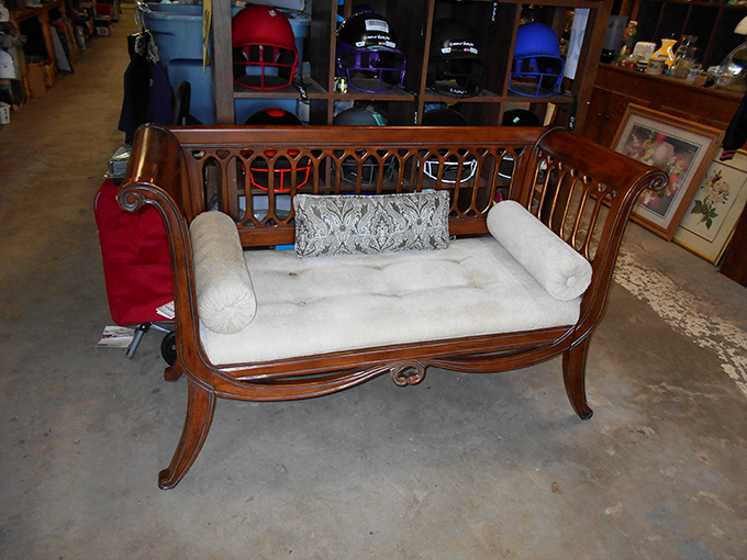Furniture that tells stories sits patiently for its next chapter. This elegant settee has probably hosted more gossip than a small-town diner.