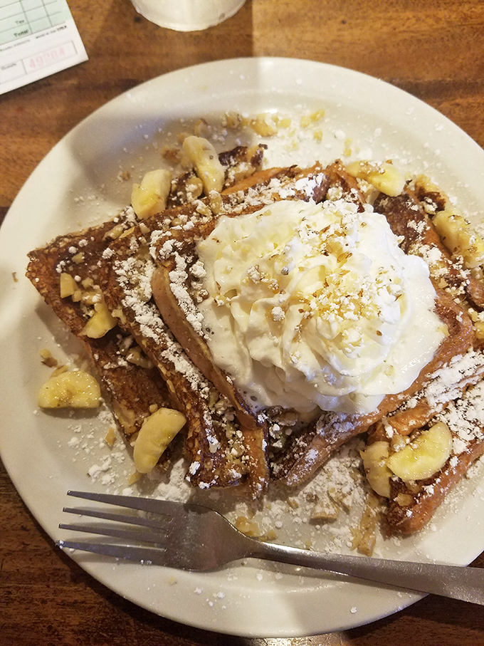 French toast that's dressed for success with powdered sugar, whipped cream, and bananas &ndash; breakfast masquerading as dessert, and nobody's complaining.