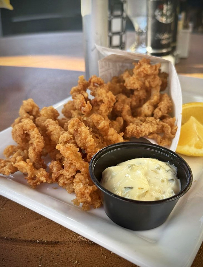 Golden-fried clam strips that crunch like autumn leaves, paired with a dipping sauce that makes seafood sing its siren song.