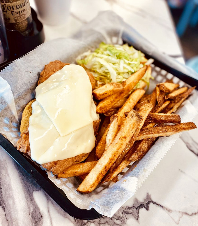 A fried grouper sandwich that's having an identity crisis as a work of art. That melted cheese blanket isn't just food&mdash;it's comfort in edible form.